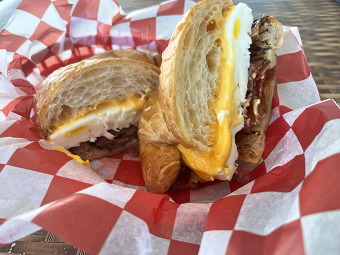 Breakfast nirvana achieved: a croissant that shatters perfectly, cradling melty cheese and bacon in its buttery embrace.