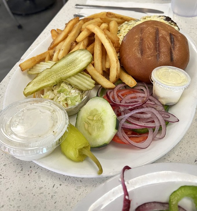 A proper burger served with crisp fries, crunchy pickles, and all the fixings&mdash;proof that sometimes the classics need no improvement, just proper execution.