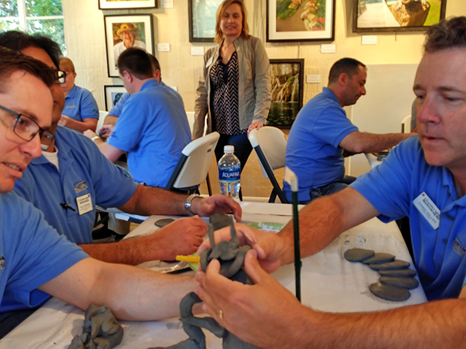 Hands work clay into shape during a workshop, where concentration and creativity merge as participants discover the therapeutic joy of tactile art-making.