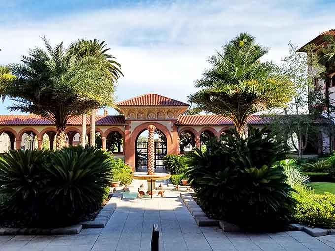 The courtyard garden offers a tranquil retreat where palm trees and tropical plants frame architectural details worthy of a Spanish palace.