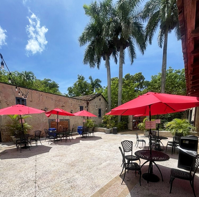 Red umbrellas pop against neutral stonework, creating impromptu outdoor living rooms where families refuel between swimming sessions.