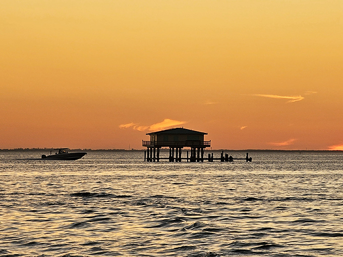 As day surrenders to dusk, Stiltsville transforms into silhouettes against a tangerine sky, like paper cutouts from a Florida dream.