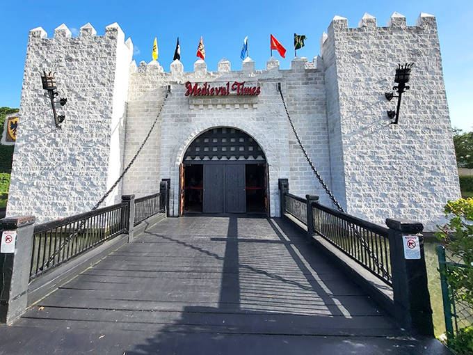 Medieval Times castle entrance welcomes guests with its imposing stone gateway, drawbridge, and medieval flags fluttering in the Florida breeze.
