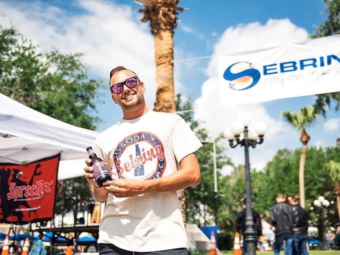 A festival-goer proudly displays his craft soda find at the Sebring Soda Festival, where hundreds of unique flavors await discovery.