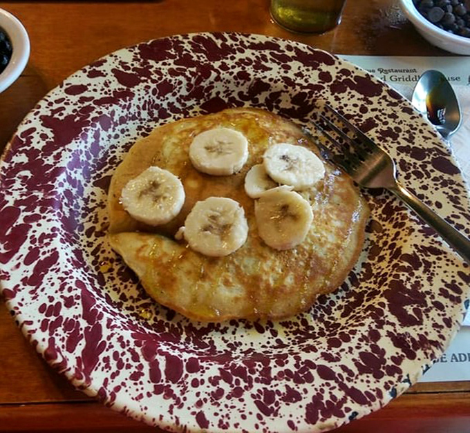 Simple pleasures: a banana-topped pancake glistening with syrup, proving sometimes less is deliciously more.