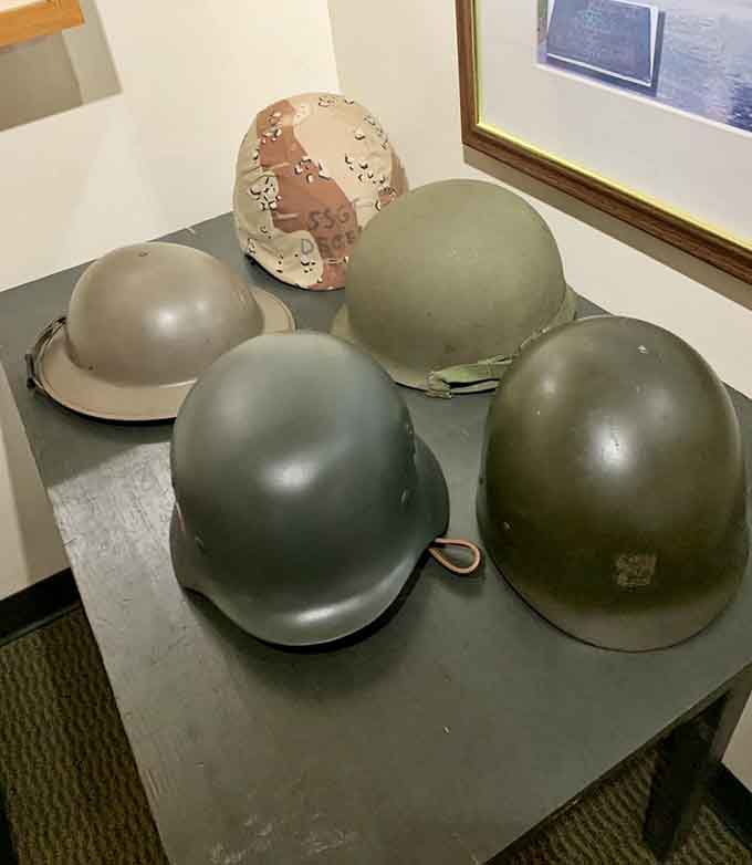 Military helmets from different eras show the evolution of protection, some bearing dents that tell harrowing survival stories.