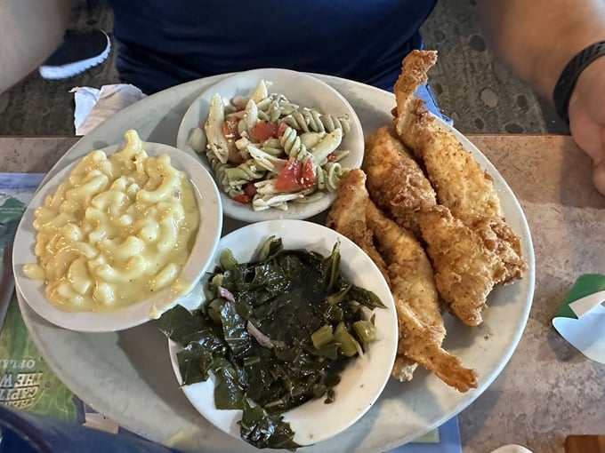 Crispy fried chicken strips with sides of mac and cheese, collard greens, and pasta salad &ndash; Southern comfort on a plate.