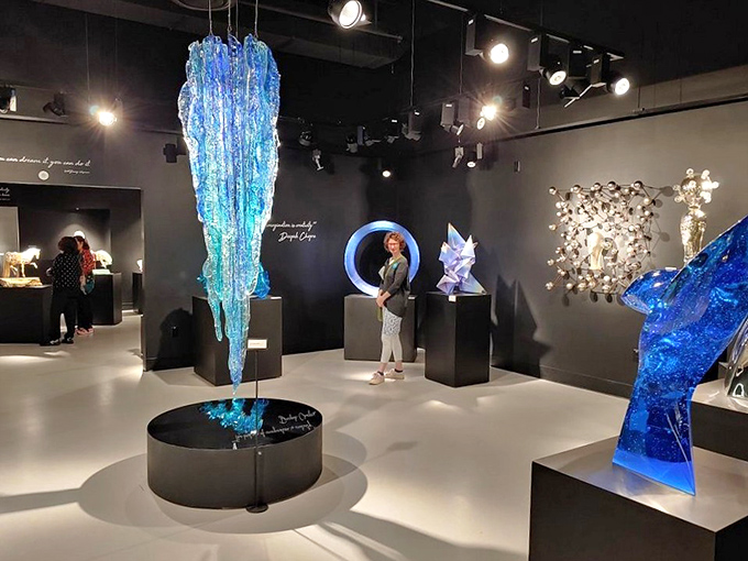 Visitors explore contemporary glass sculptures that transform the solid material into what appears to be liquid movement captured in time.