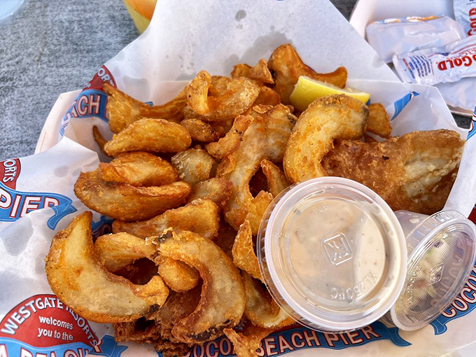 Golden-brown fish and chips – the ultimate pier food – served in a basket lined with branded paper, simple perfection with ocean breezes.