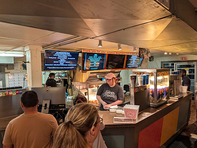 Inside the concession stand, staff prepare classic movie treats while patrons decide between traditional favorites and modern additions.