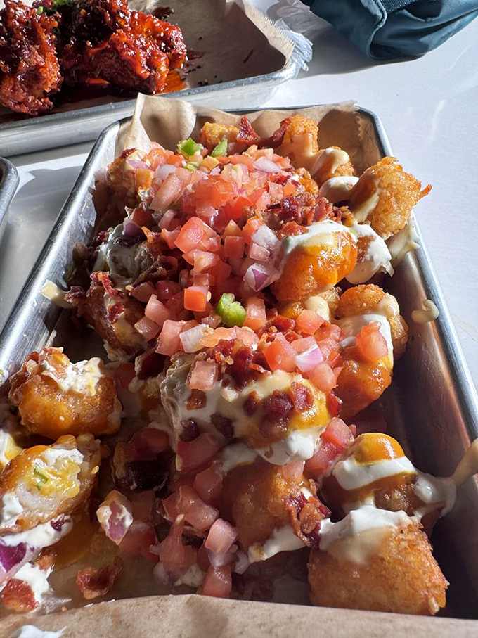 Loaded tots that defy gravity &ndash; crispy potato nuggets buried under an avalanche of cheese, bacon, and fresh tomato that somehow still maintain their crunch.