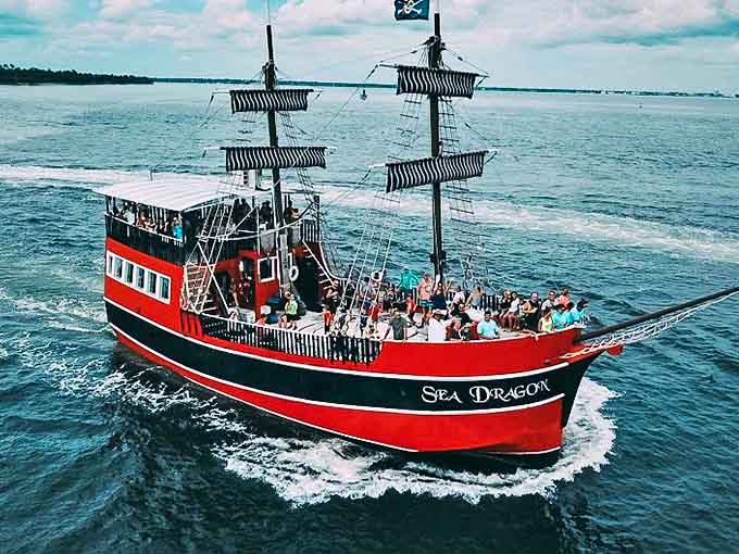 From above, the Sea Dragon resembles a crimson jewel against the emerald waters, carrying its cargo of temporary pirates across the bay.
