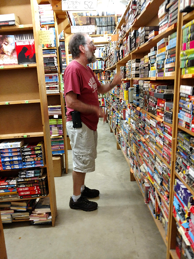 The quintessential bookstore moment: a reader lost in concentration, hunting for that perfect title among thousands of possibilities.