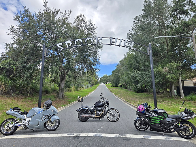 Motorcycle enthusiasts gather under the famous archway, their bikes perfectly positioned to document their brush with Florida's paranormal roadway.