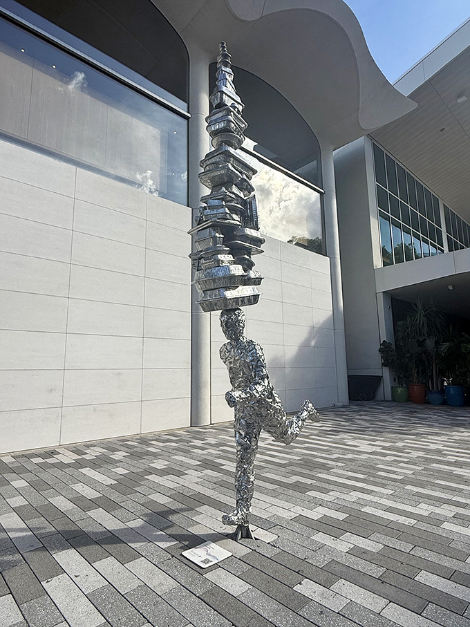 Art meets playground as this silver figure balances impossible objects, mirroring the tower's blend of artistic vision and childlike joy.