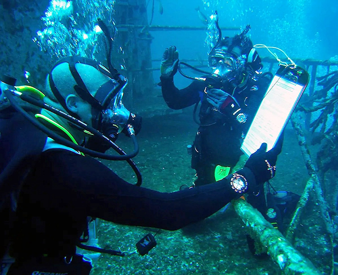 Two divers compare notes on their underwater adventure, using slates to communicate where words fail beneath the waves.