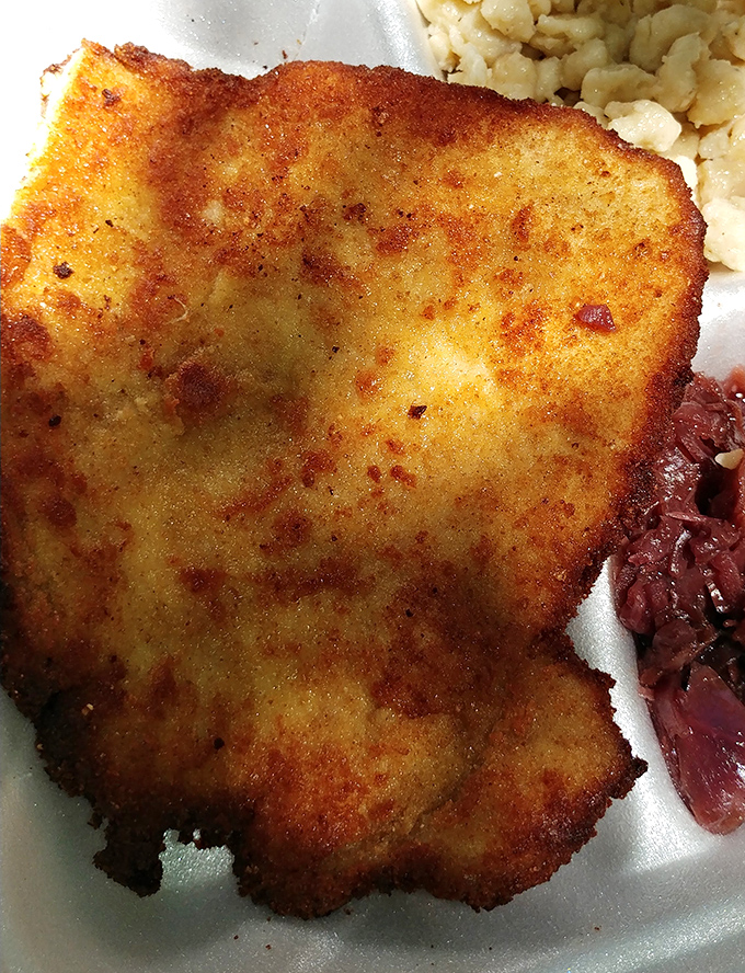The chicken schnitzel without its bun reveals the golden, crispy coating that makes this dish legendary, looking like it just won a beauty pageant.