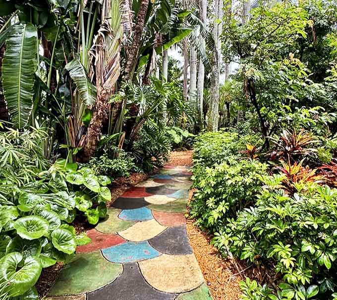 A whimsical mosaic pathway winds through dense greenery, each colorful stone like a breadcrumb leading deeper into wonderland.