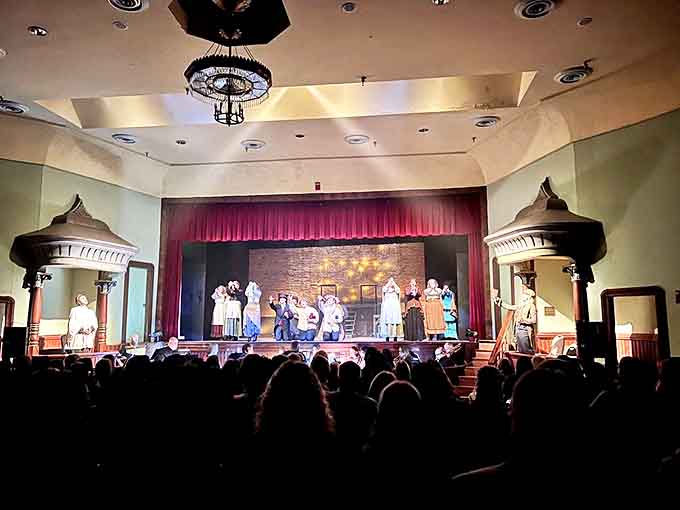 The audience sits captivated as performers bring history to life, the ornate architectural details of the theater adding authenticity to every scene.