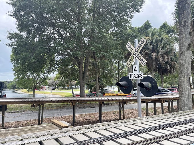 Classic railroad crossing signals stand guard over the miniature tracks. Even at this scale, safety comes first on this delightfully diminutive railway.