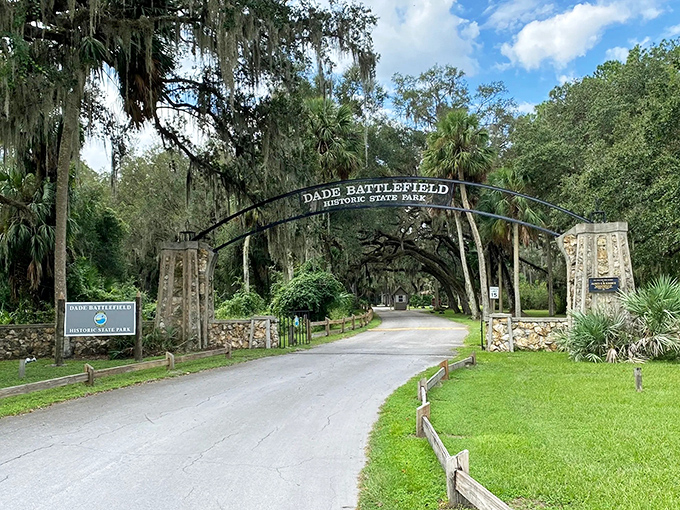 The iconic entrance to Dade Battlefield Historic State Park, where Spanish moss-draped trees create a natural archway into Florida's rich past.