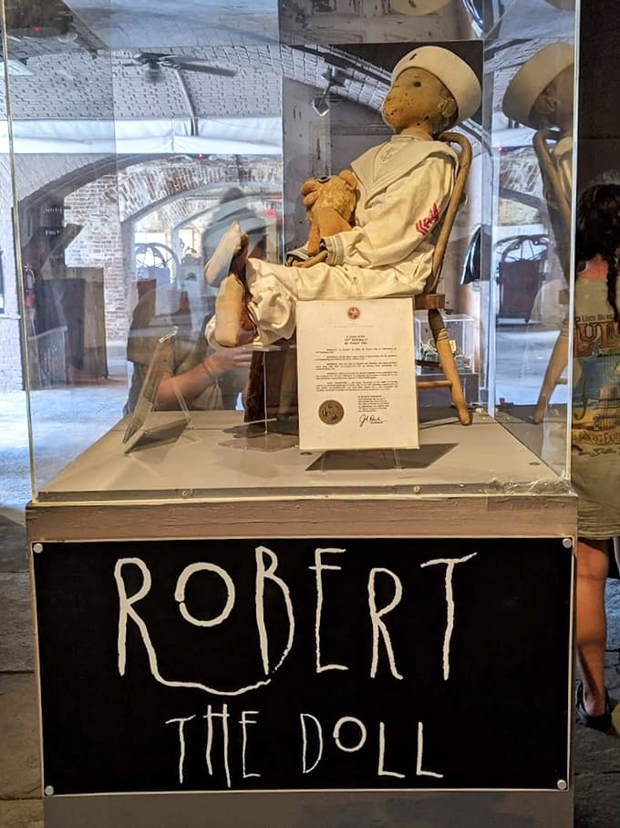 Robert the Doll sits in his glass case wearing his sailor suit, looking innocent while terrifying visitors with his allegedly cursed presence.