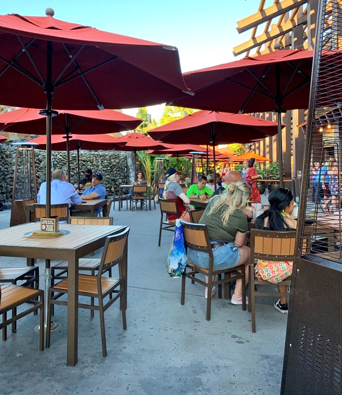 Trader Sam's outdoor terrace offers a more subdued experience with comfortable seating under bright red umbrellas and Disney magic in the distance.