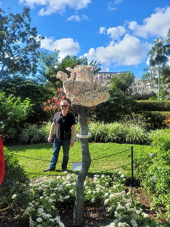 Colorful mosaic sculpture catches sunlight among flowering plants, a permanent rainbow in this botanical paradise.
