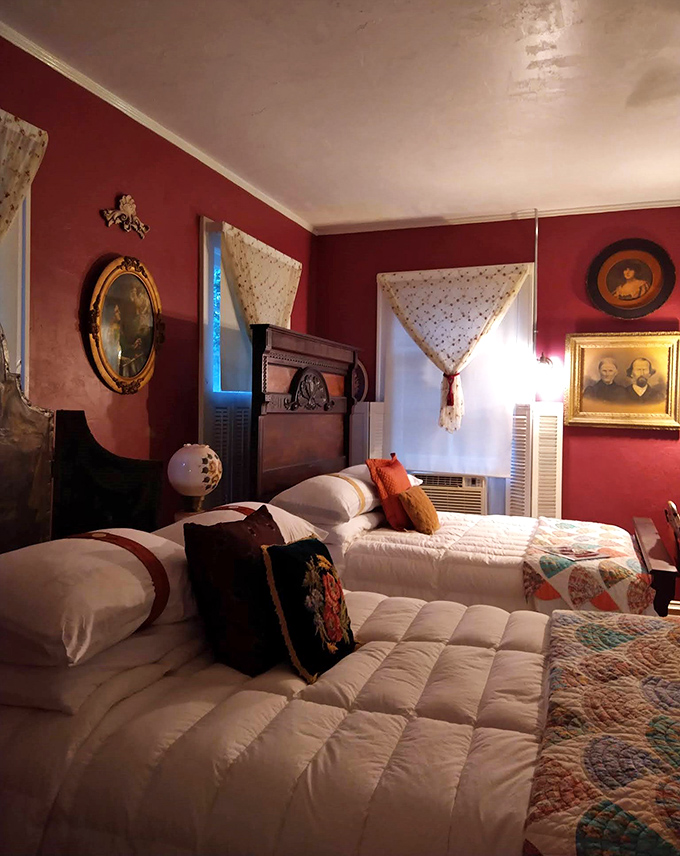 Twin beds with handmade quilts invite weary travelers in this crimson-walled bedroom, where antique portraits seem to follow you with their eyes.