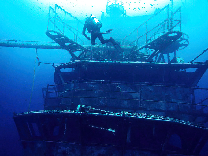The ship's superstructure creates an otherworldly silhouette against the blue backdrop, like a sci-fi cityscape where barracudas replace taxis.