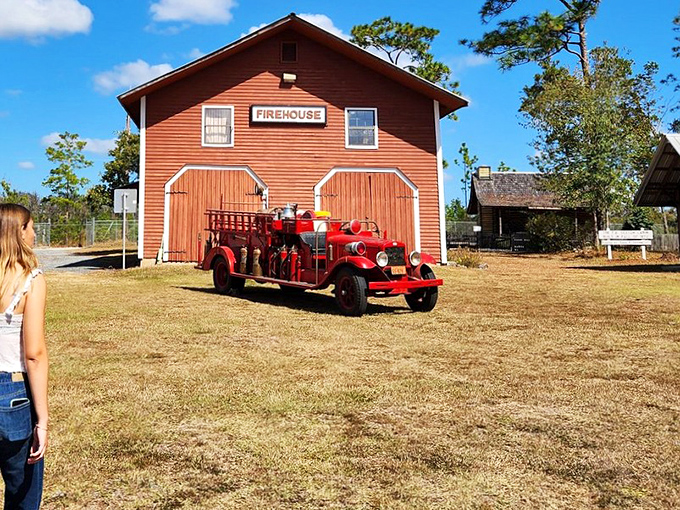 This vintage fire truck stands ready outside the bright red Firehouse, a reminder that community safety once depended on bucket brigades.