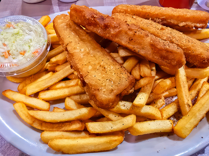 Crispy battered fish sticks with fries create a mountain of fried goodness that would make any seafood lover weep with joy and anticipation.