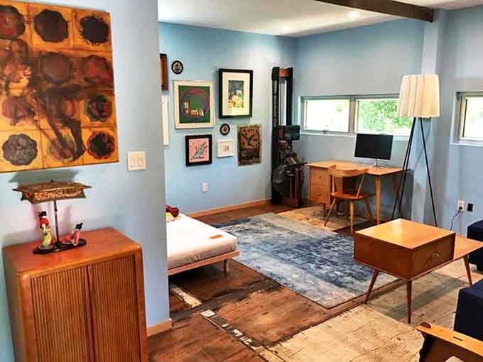 Mid-century modern furniture and vibrant artwork transform this container space into a living gallery where comfort meets creative expression.