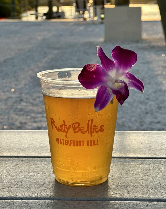 A cold draft beer adorned with an orchid &ndash; because at Rusty Bellies, even your drink gets dressed up for the view.