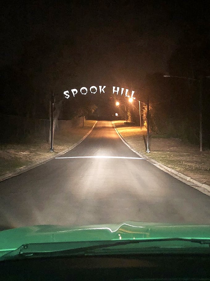 Spook Hill after dark adds an extra layer of eerie atmosphere &ndash; the illuminated sign beckoning brave nighttime visitors to test the ghostly legend.