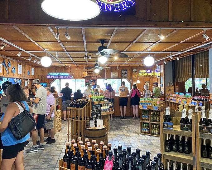 Store area: Customers browse wooden displays filled with colorful bottles, each representing a different tropical fruit transformed into wine.