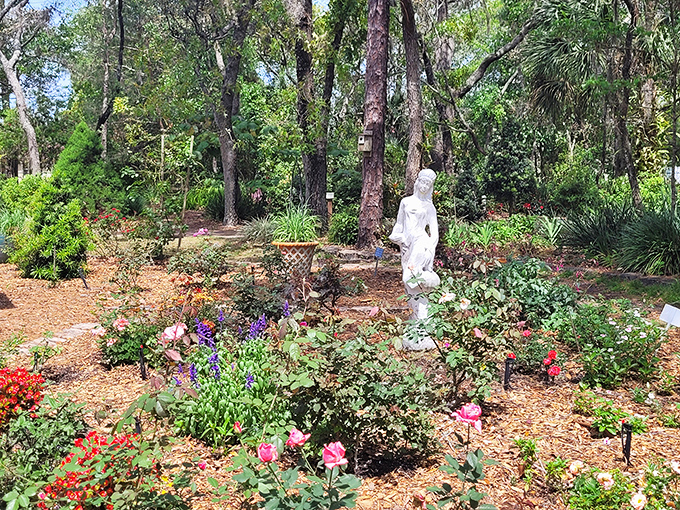 Summer blooms create a tapestry of color against ancient statuary, where classical art meets wild botanical abundance in perfect harmony.