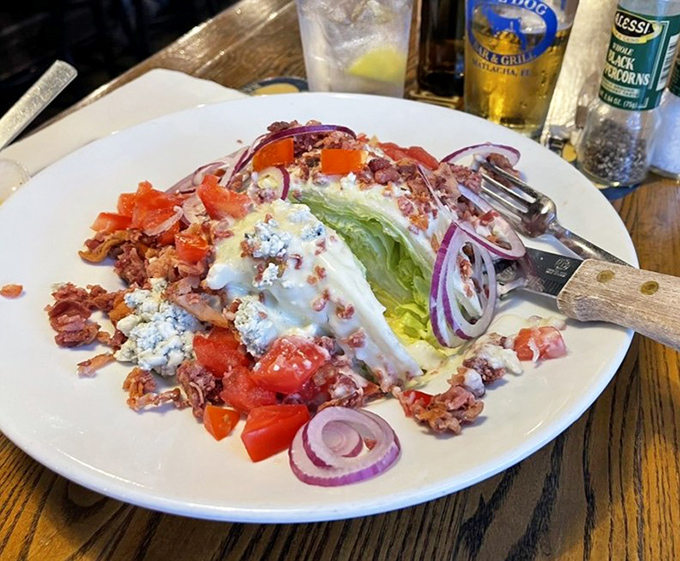 The wedge salad arrives like an edible sculpture &ndash; crisp lettuce, ripe tomatoes, and bacon crumbles creating a symphony of textures.