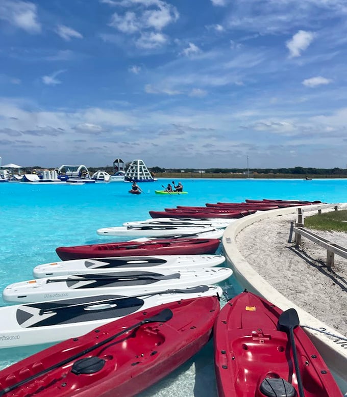 A flotilla of kayaks standing ready like colorful chariots awaiting water-bound adventurers with questionable paddling skills.