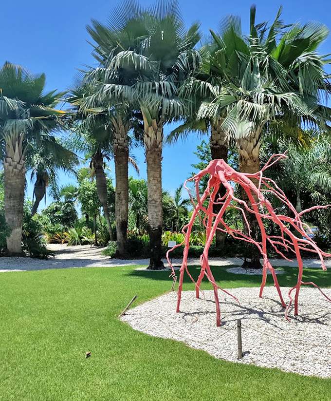 Towering palms stand sentinel around a striking red sculpture, creating a perfect contrast of natural and artistic elements.