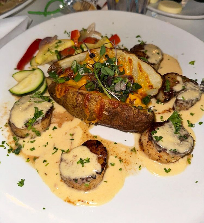 Blackened scallops surround a loaded baked potato like sentinels of flavor, swimming in a buttery sauce that demands bread for sopping.