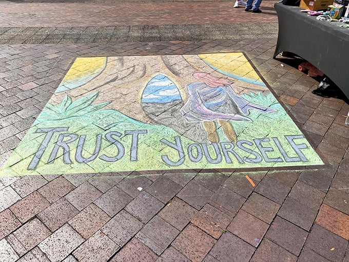 "Trust Yourself" declares vibrant chalk art on the brick pavement &ndash; temporary wisdom that washes away with rain but lingers in memory.