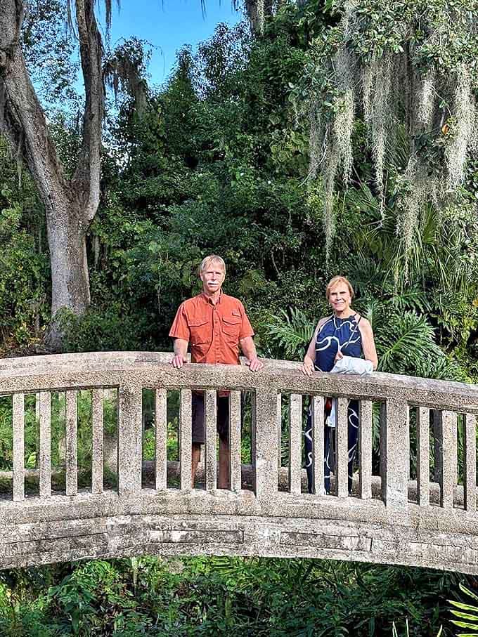 Visitors pause on one of the property's signature bridges, surrounded by Spanish moss and tropical foliage that frame this concrete curiosity.