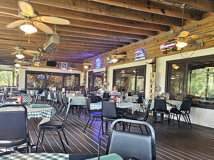 The screened porch offers a breezy Florida dining experience where ceiling fans keep things cool while checkered tablecloths add homey charm.