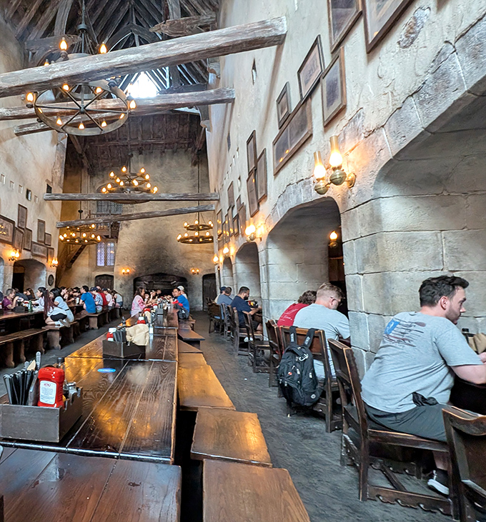 Long communal tables invite shared stories and new friendships, while medieval chandeliers cast a warm glow over hungry adventurers.