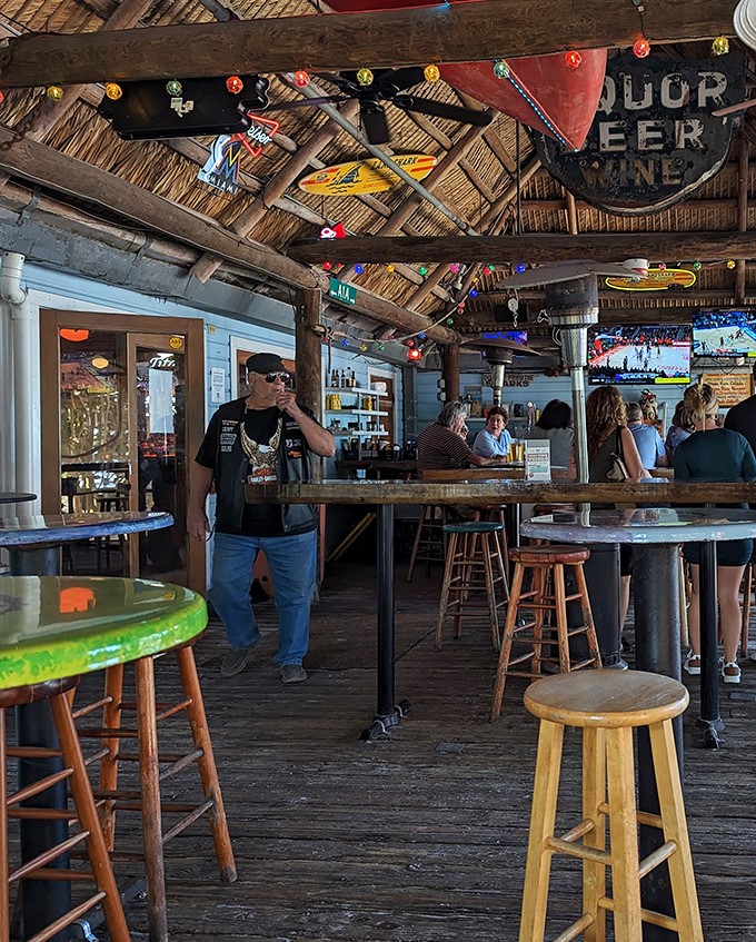 Casual coastal vibes: The covered bar area features colorful string lights, surfboards, and a laid-back atmosphere where Florida time moves at its own pace.
