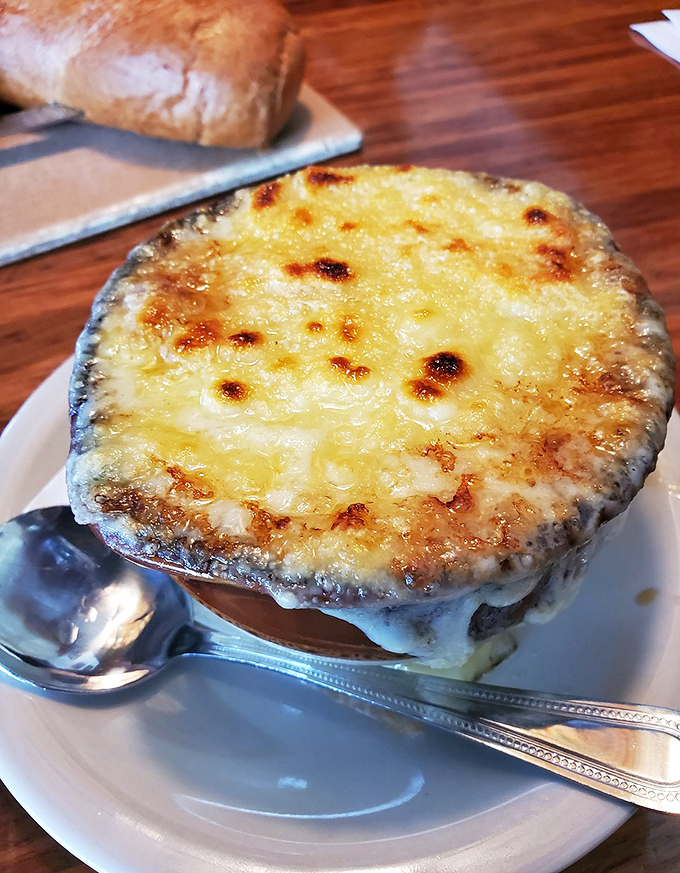 Beneath that golden crown of bubbling cheese lies a French onion soup so rich it could buy a yacht.
