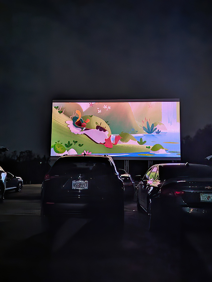 As darkness falls, the screen comes alive with vibrant animation, transforming parked cars into personal theaters under the stars.