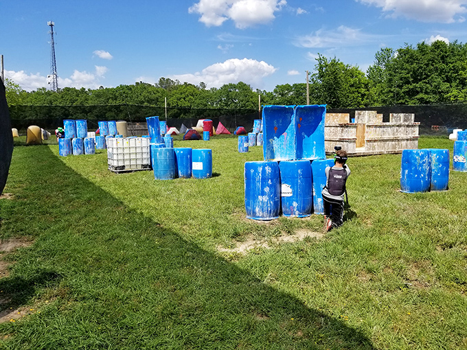 Blue barrels create a tactical playground where friendly competitors trade colorful "ammunition" and even more colorful commentary.