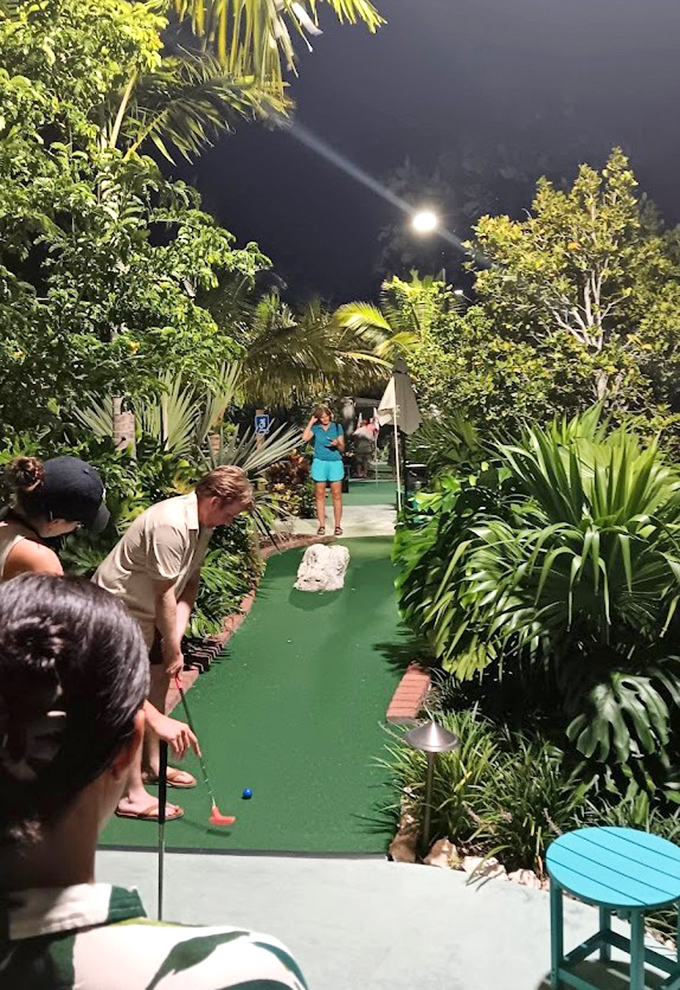 Porky's mini-golf course transforms after dark into a tropical garden adventure, where putting under palm trees becomes an evening highlight.